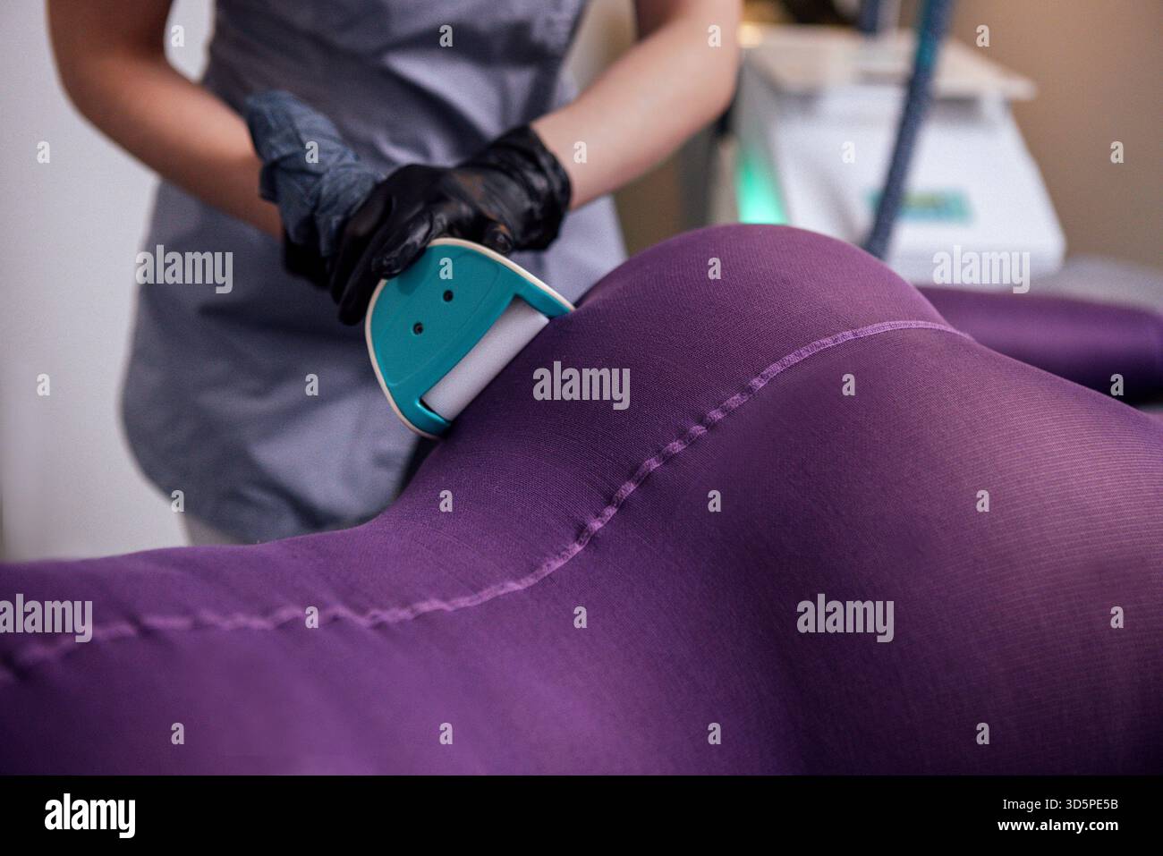 Technician in gray uniform applies LPG roller to purple fabric ...