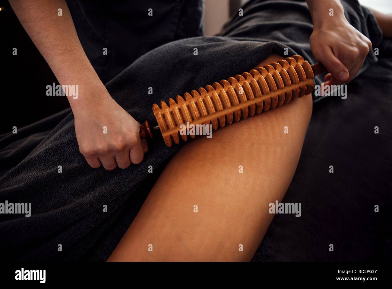 Madeira massage therapist applies wooden roller to client's thigh ...