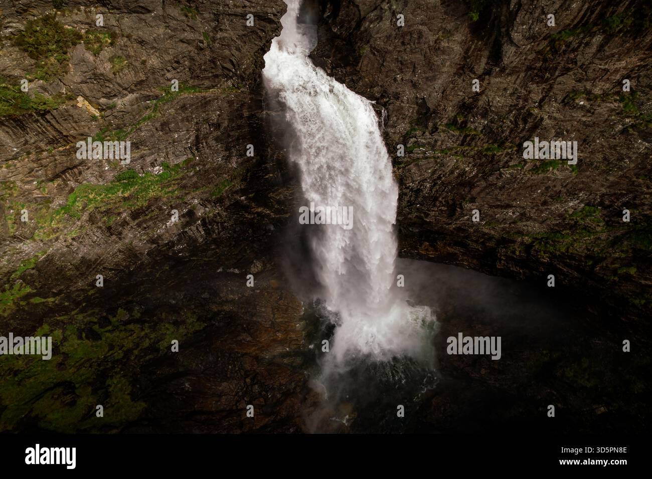 Aerial view of white water cascade roaring down the rugged, dark cliffs ...