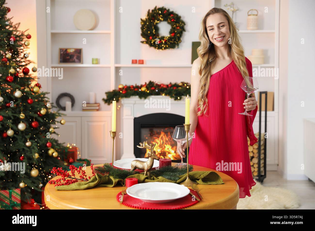 Beautiful woman setting table in room decorated for Christmas. Space ...