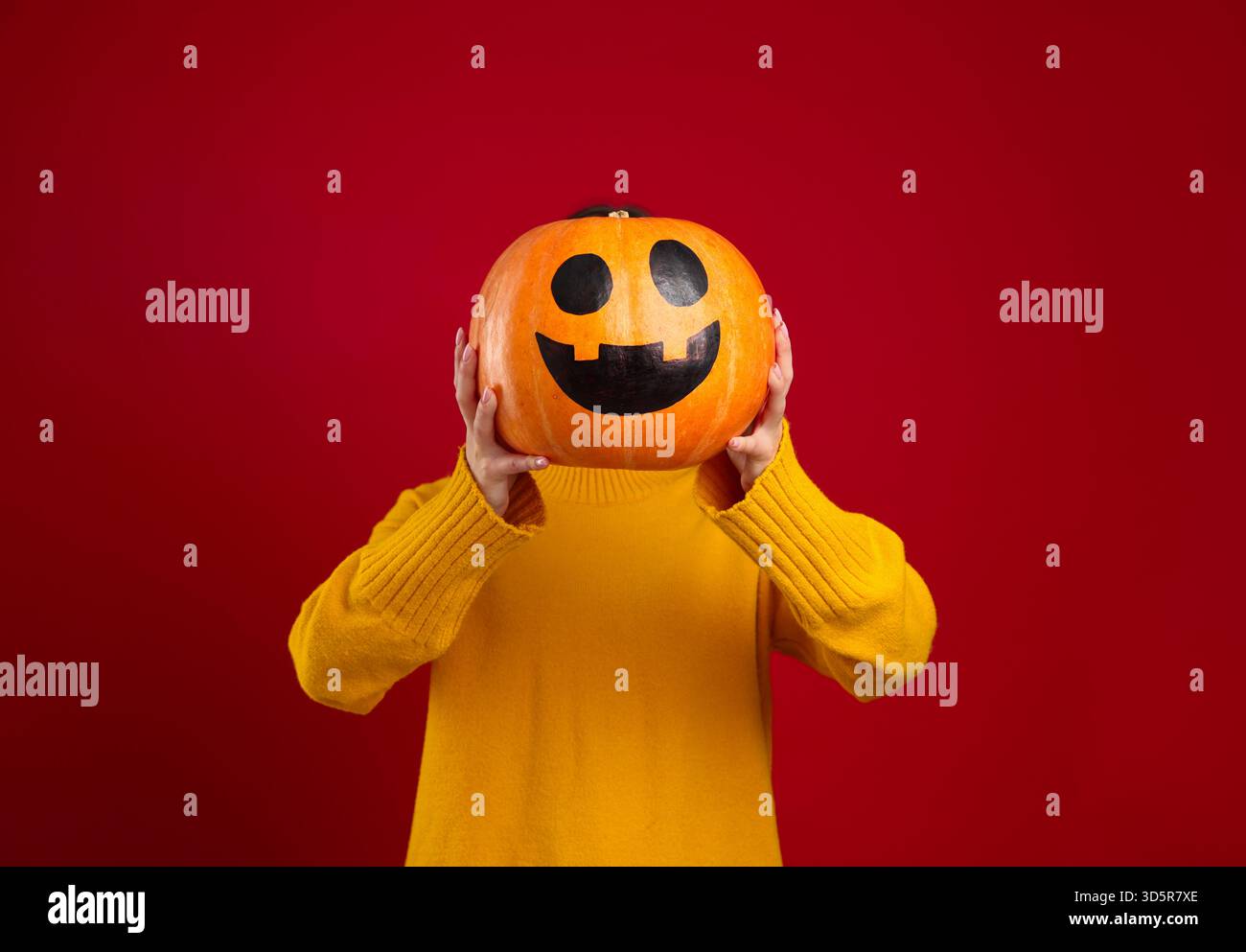 Happy Halloween. Woman hiding behind pumpkin with face drawing on red ...