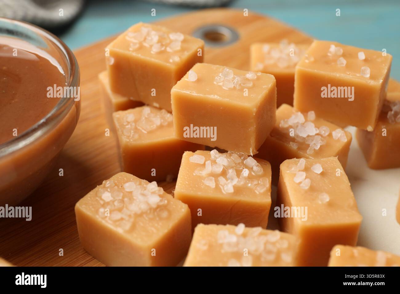 Tasty candies with salt and caramel sauce on light blue table, closeup ...