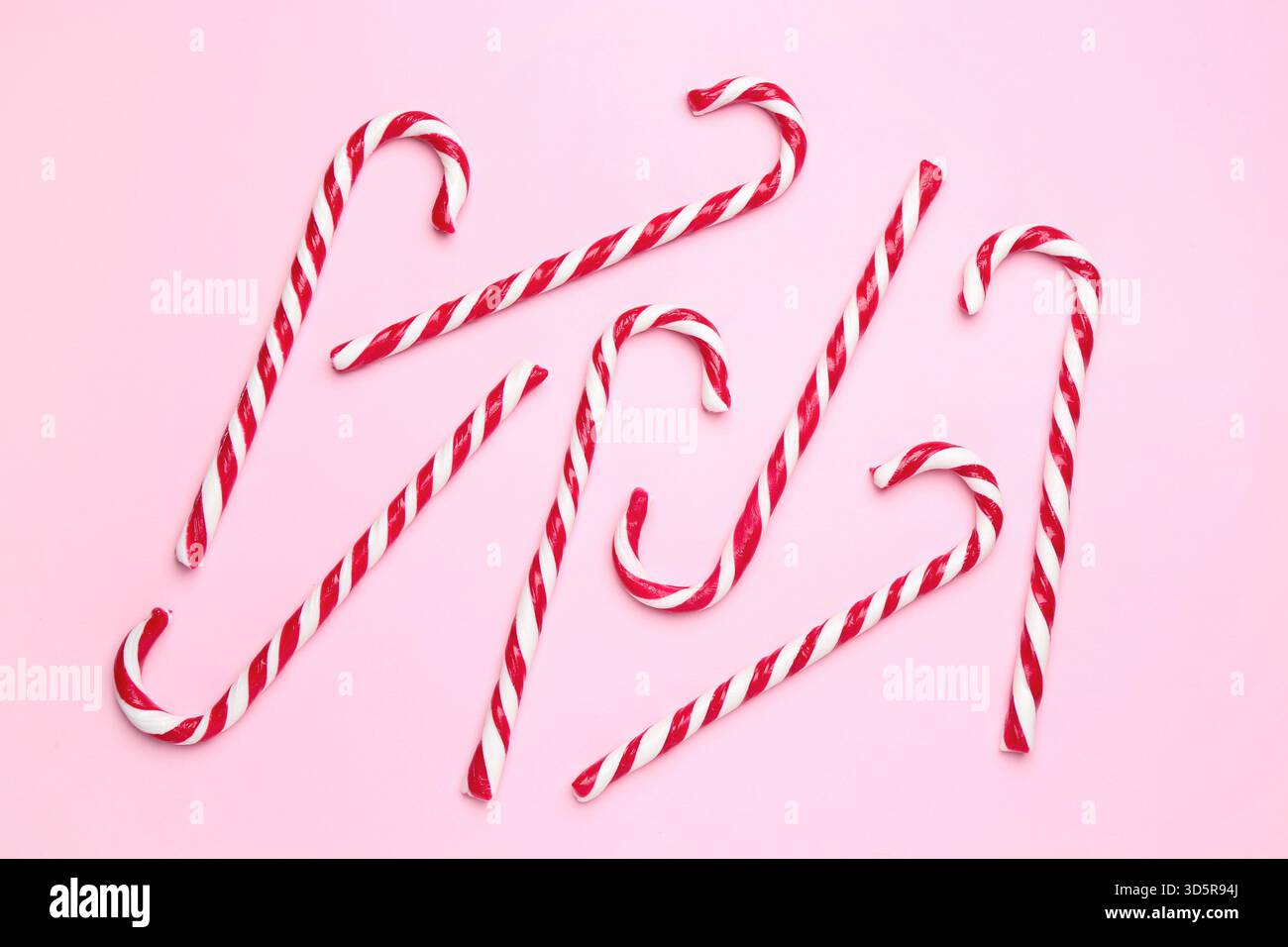 Merry Christmas and Happy New Year. Tasty candy canes on pink ...
