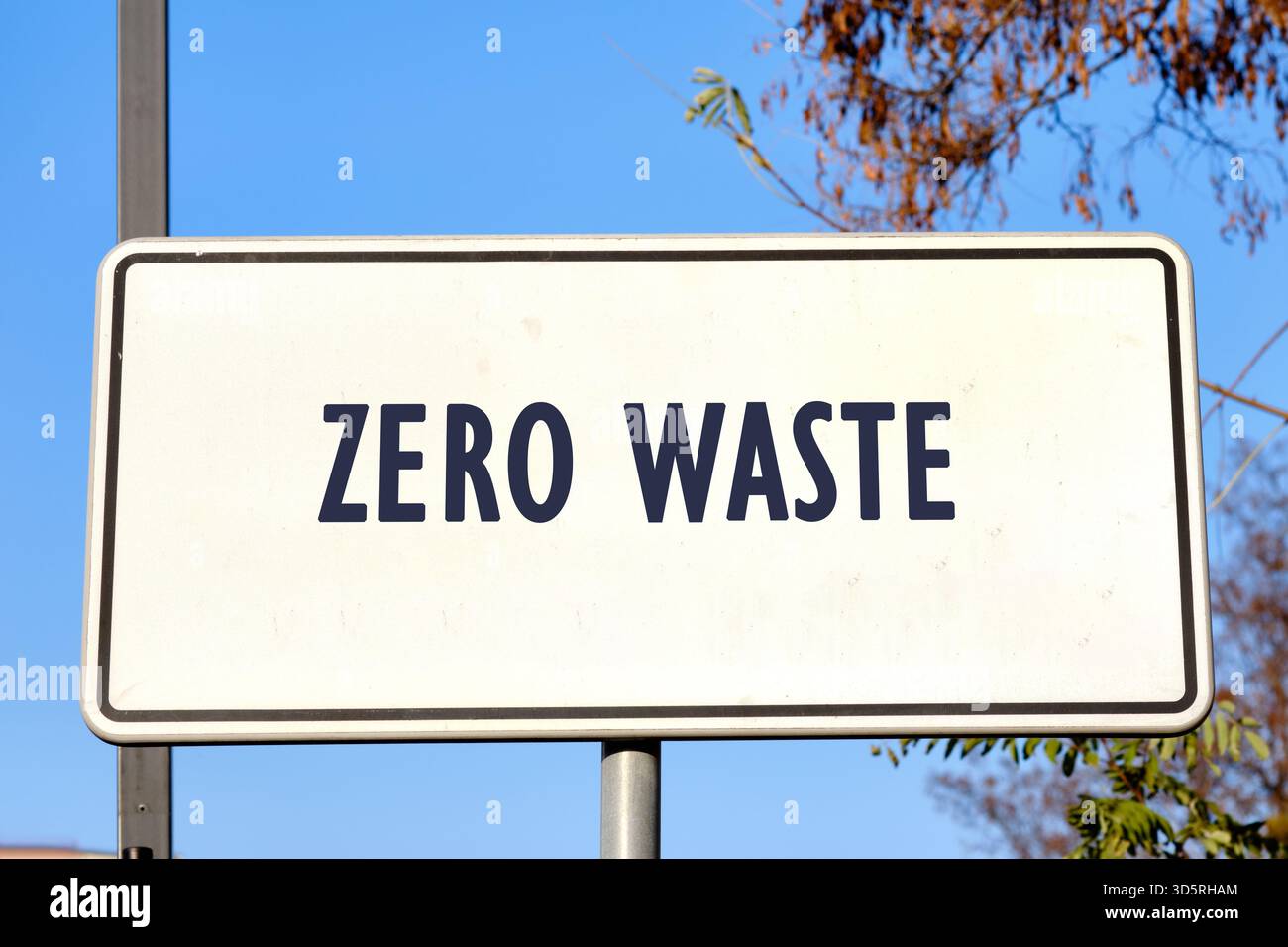 A rectangular white sign with a black border displays the words ZERO ...