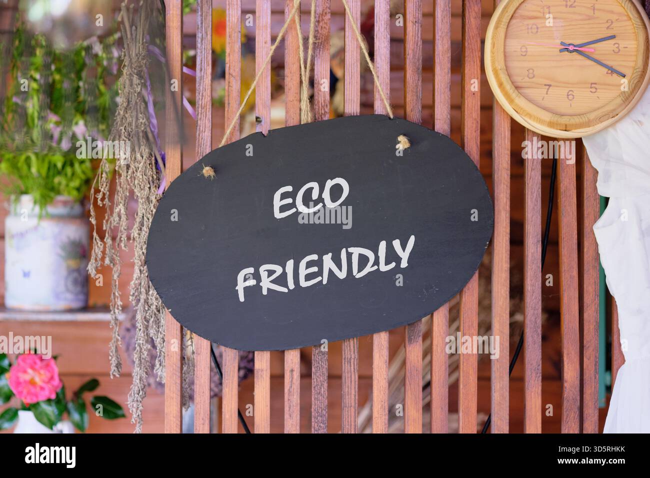 A round, dark sign proclaims Eco Friendly against a wooden backdrop ...