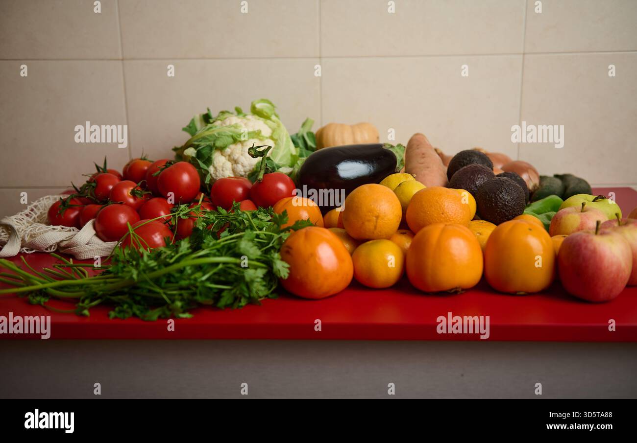 A vibrant assortment of fresh fruits and vegetables arranged on a red ...