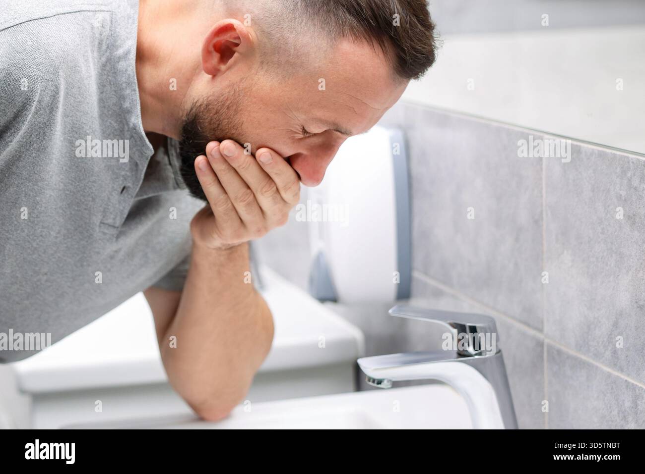 Man suffering from nausea over sink in bathroom Stock Photo - Alamy