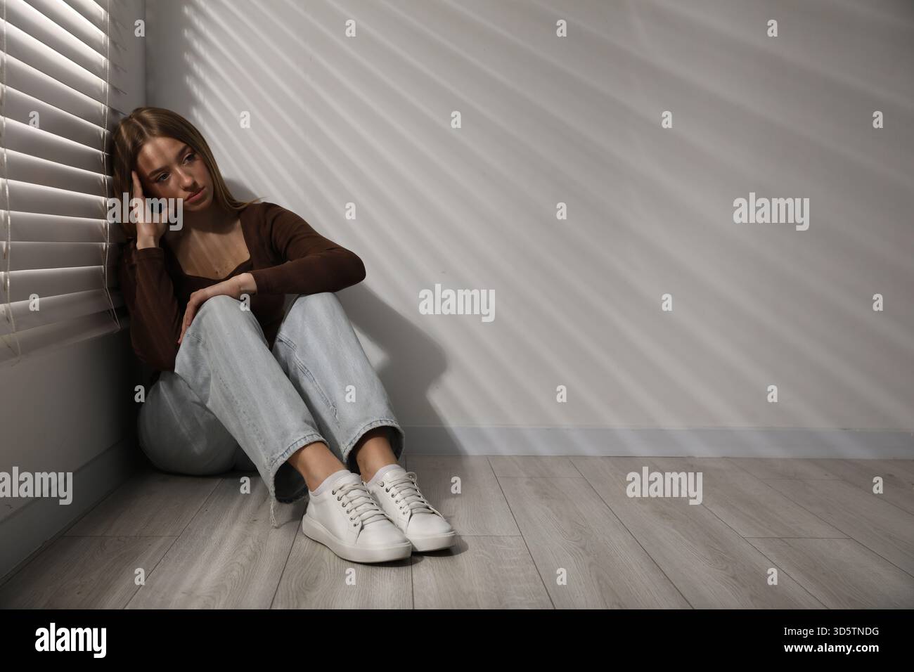 Depressed teenage girl near window at home, space for text Stock Photo ...
