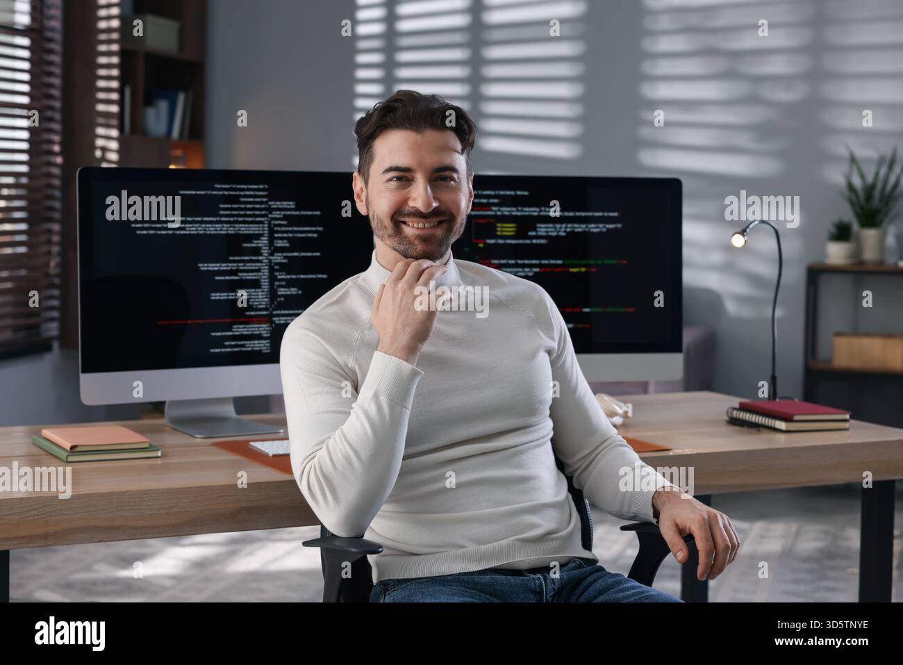 Portrait of smiling programmer on chair at workplace Stock Photo - Alamy