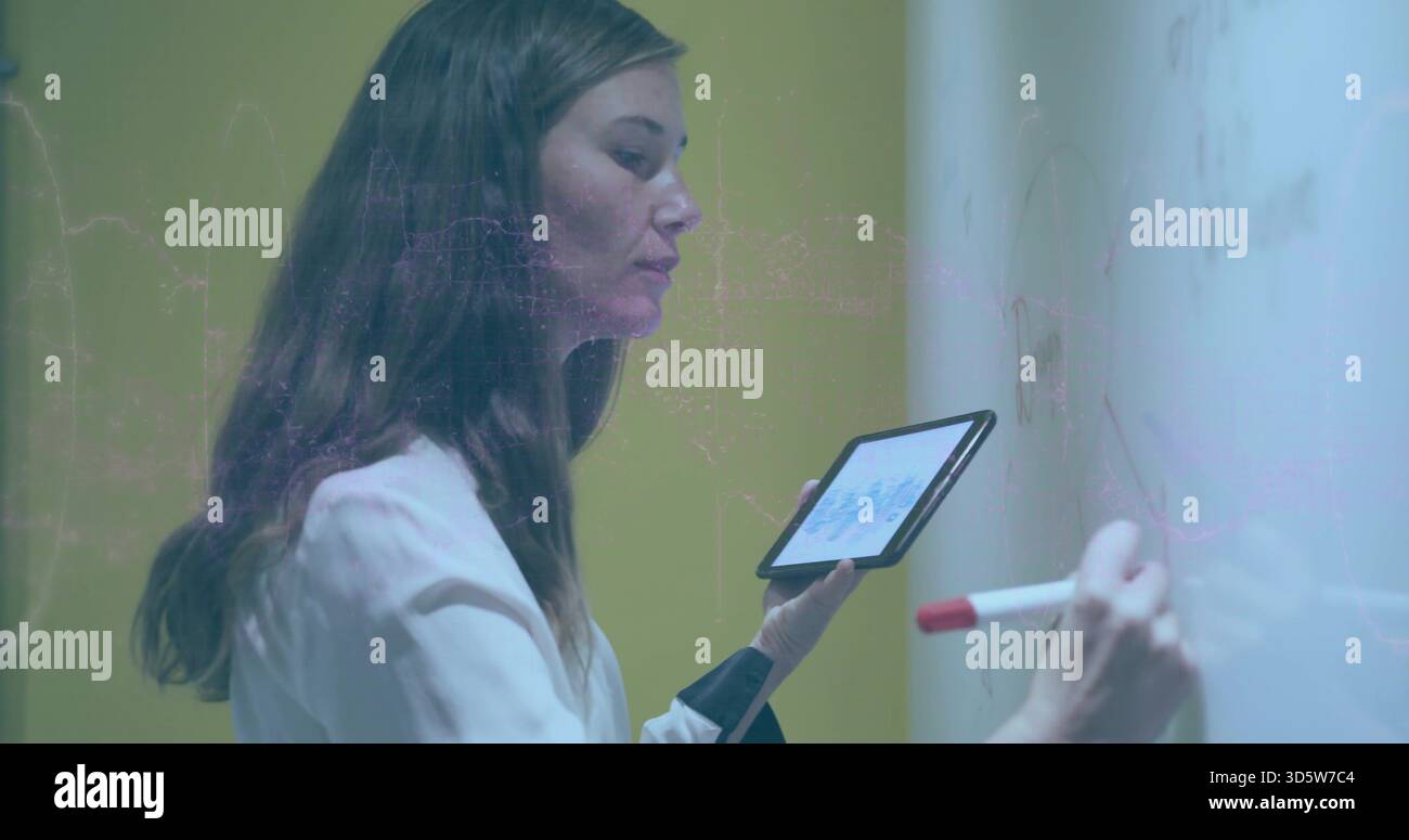 Writing woman in white blouse marking whiteboard in office with tablet ...