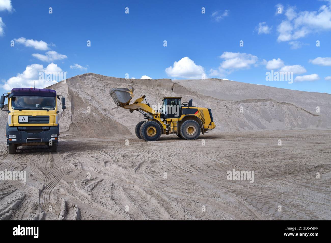 Wheel loader loads a truck with sand in a gravel pit Stock Photo - Alamy
