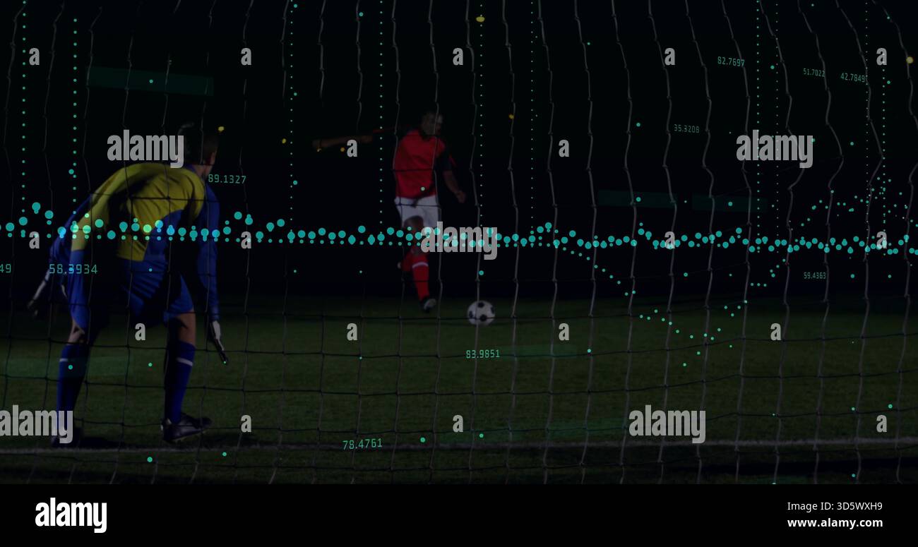 Kicking red kit player approaching soccer ball on night pitch with goal ...