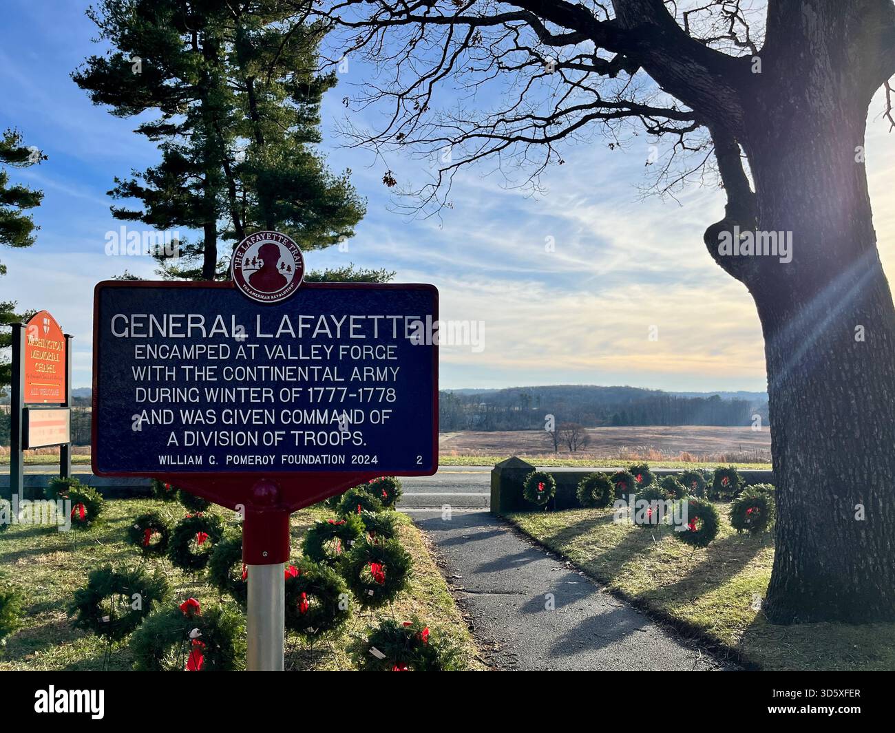 A sign that says General Lafayette is on a path. The sign is red and ...