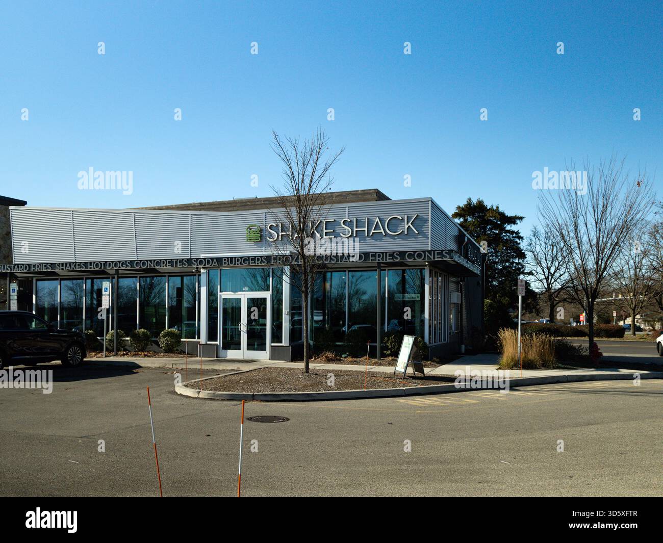 A Shake Shack restaurant with a large window and a parking lot. The ...