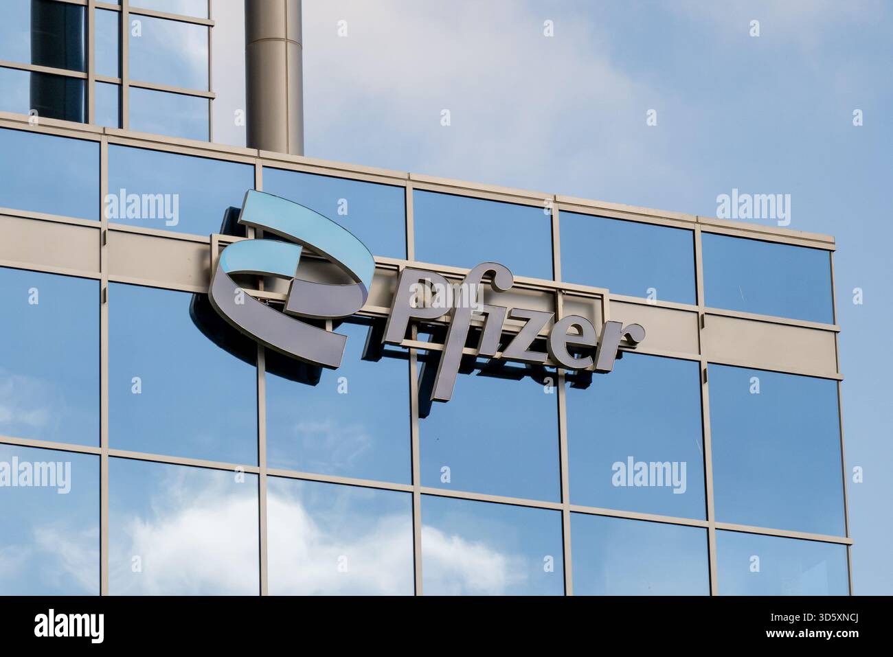 Pfizer logo on glass office building facade with sky reflections, South ...