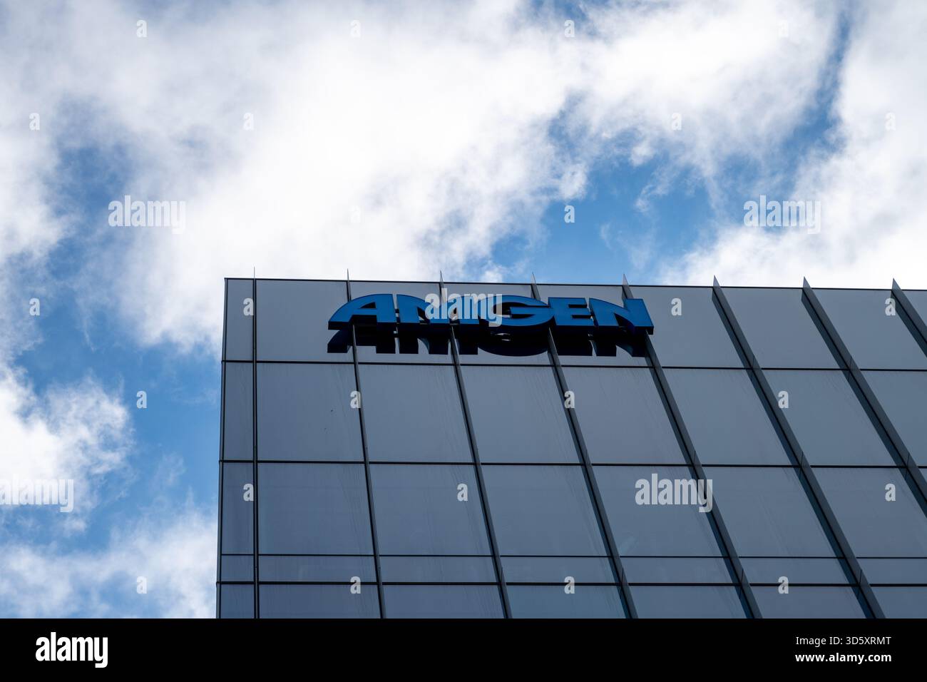 Exterior of Amgen office building with blue logo on modern glass facade ...