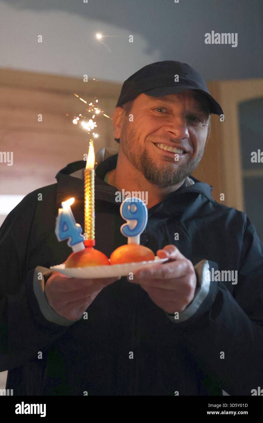 Smiling man celebrating 49th birthday with cake, candles, and a ...