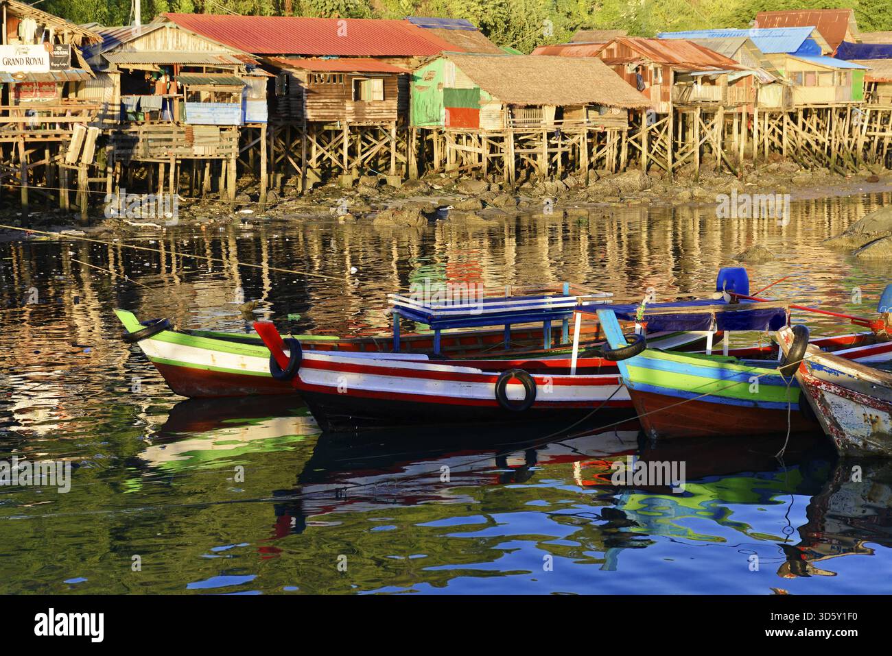 Colorful boats on water with village wooden shelters in the background ...