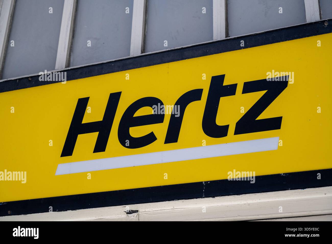 Close-up of Hertz car rental storefront sign with yellow background ...