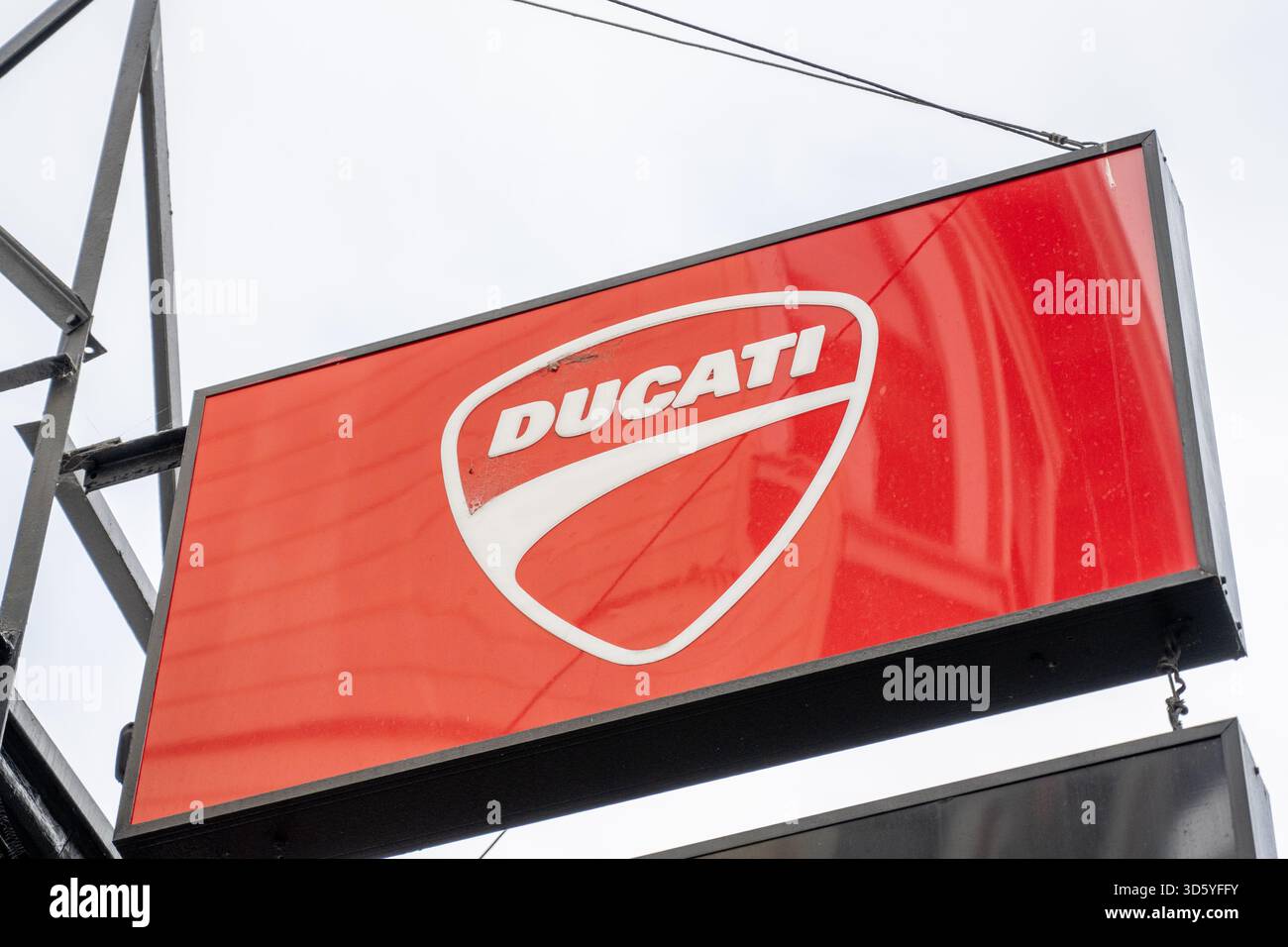 Red Ducati logo sign hanging outside a motorcycle shop on an overcast ...