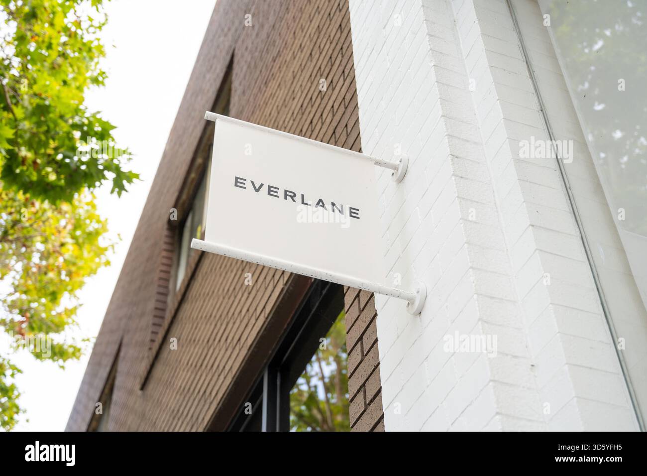 Everlane storefront blade sign on a white-painted brick facade along a ...