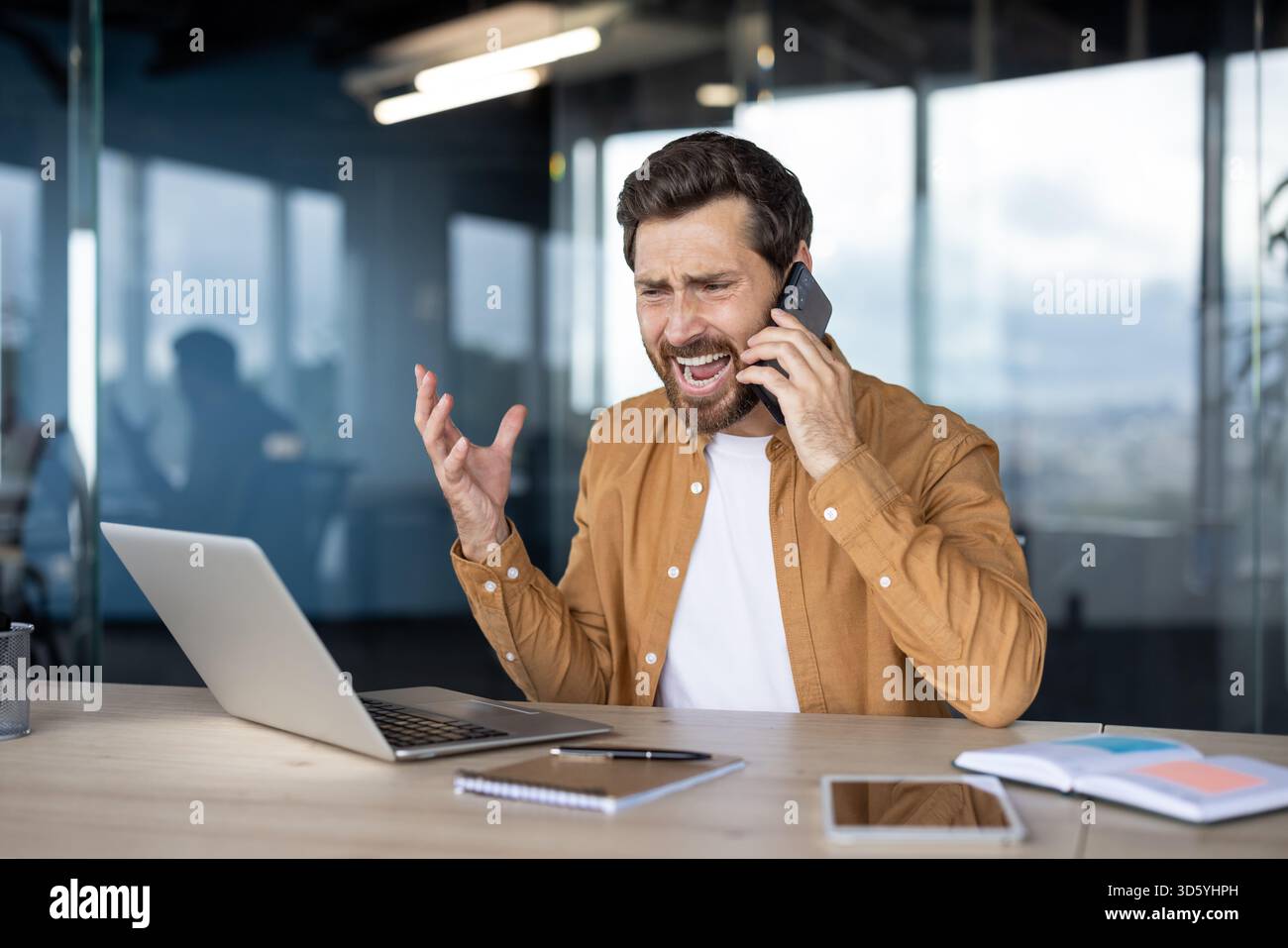 Entrepreneur in office yelling into smartphone, frustrated and stressed ...