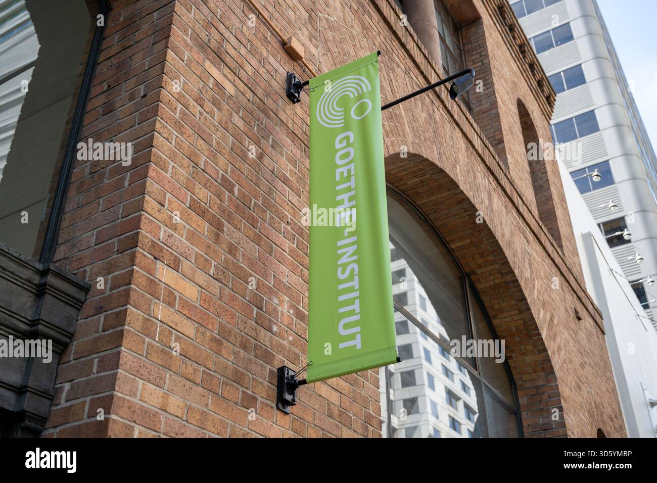 Vertical green Goethe-Institut banner mounted on brick facade with ...