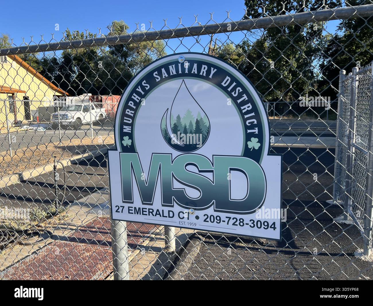 Murphys Sanitary District sign on a chain-link fence at a utility facility with construction ...