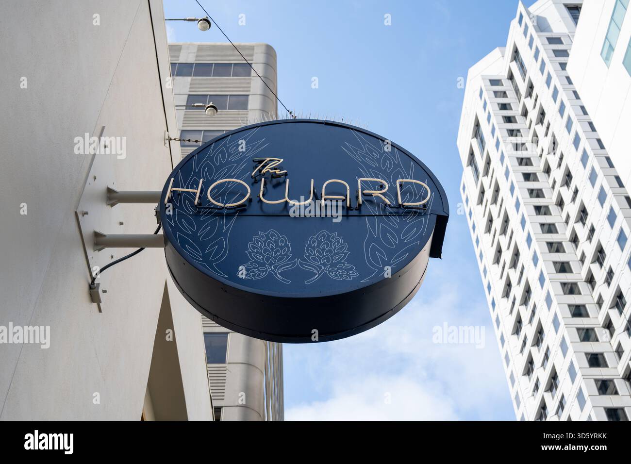 Round blue projecting sign reading "The Howard" on exterior wall with ...