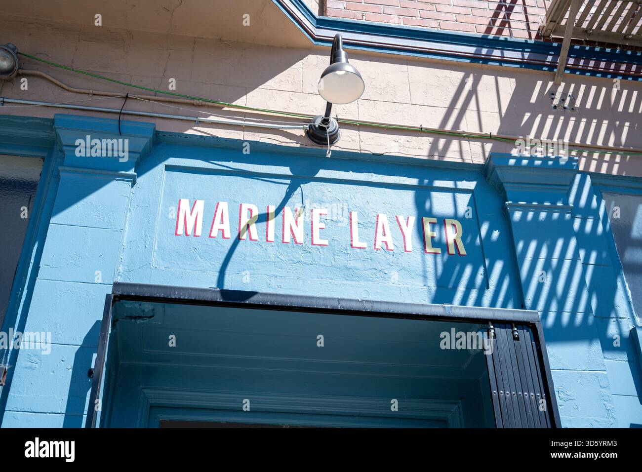 Marine Layer storefront with blue facade, overhead gooseneck light and ...