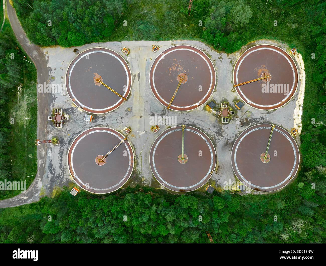 Sewage treatment plant with multiple circular tanks surrounded by trees ...
