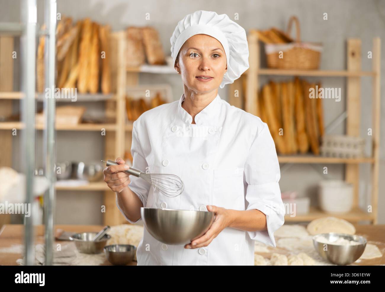 Portrait of female baker in uniform holding egg whisk Stock Photo - Alamy
