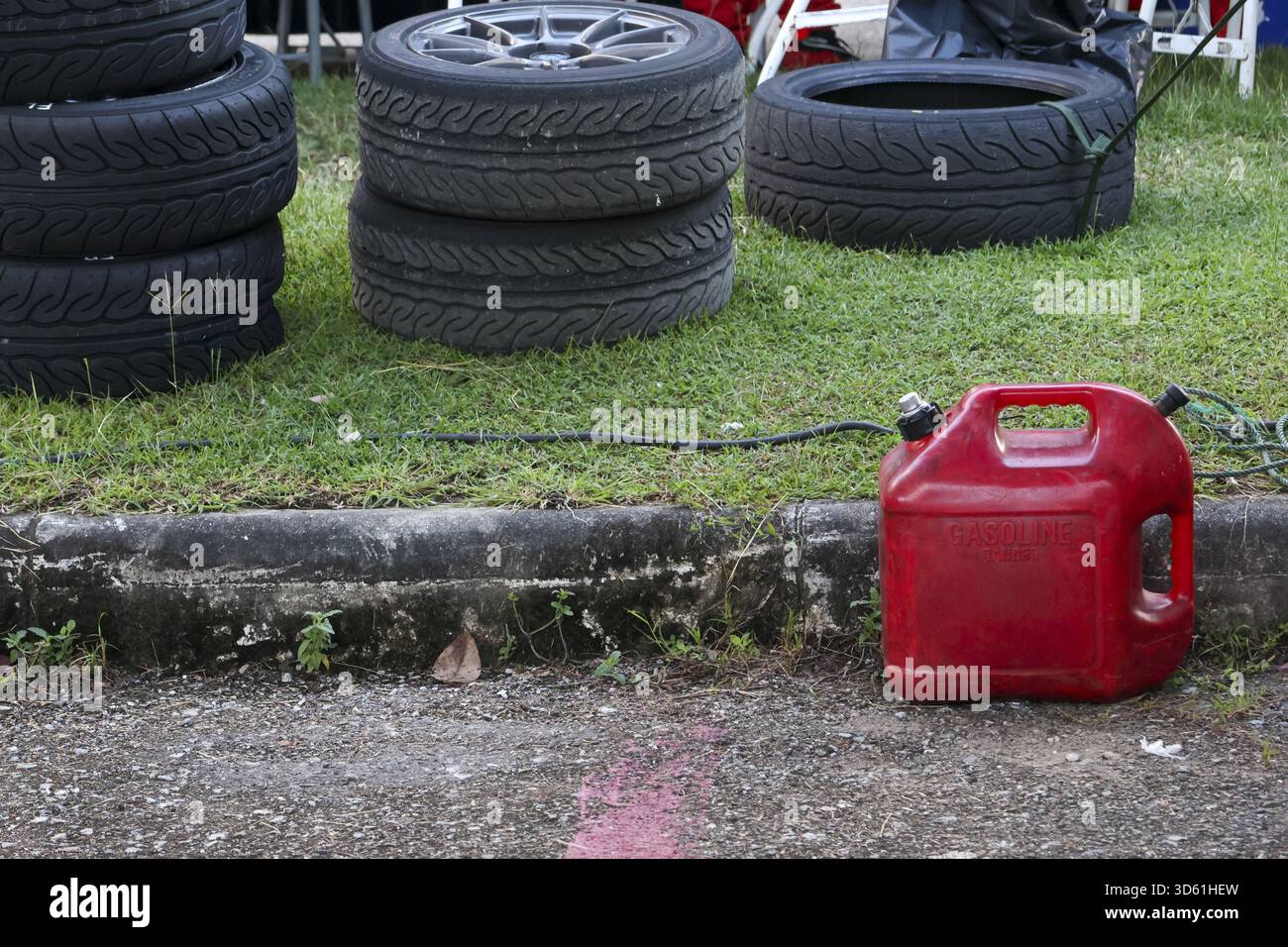 Red gas can for fuel sits on asphalt in race paddock. Stacks of ...