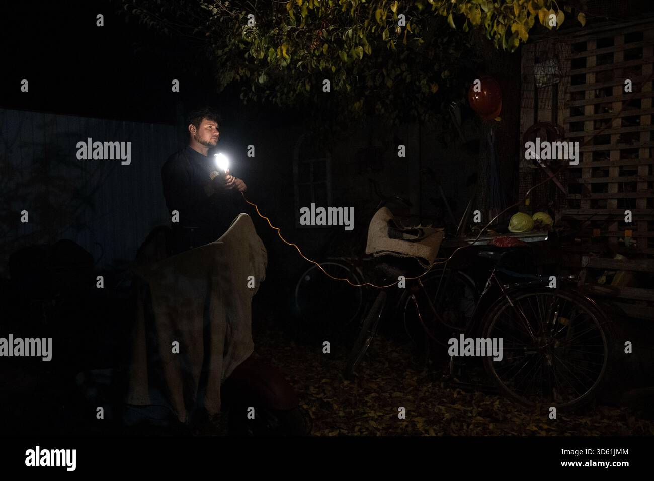 Oleksandr Tomchuk rigs up a light in his yard to fix a moped, which the ...