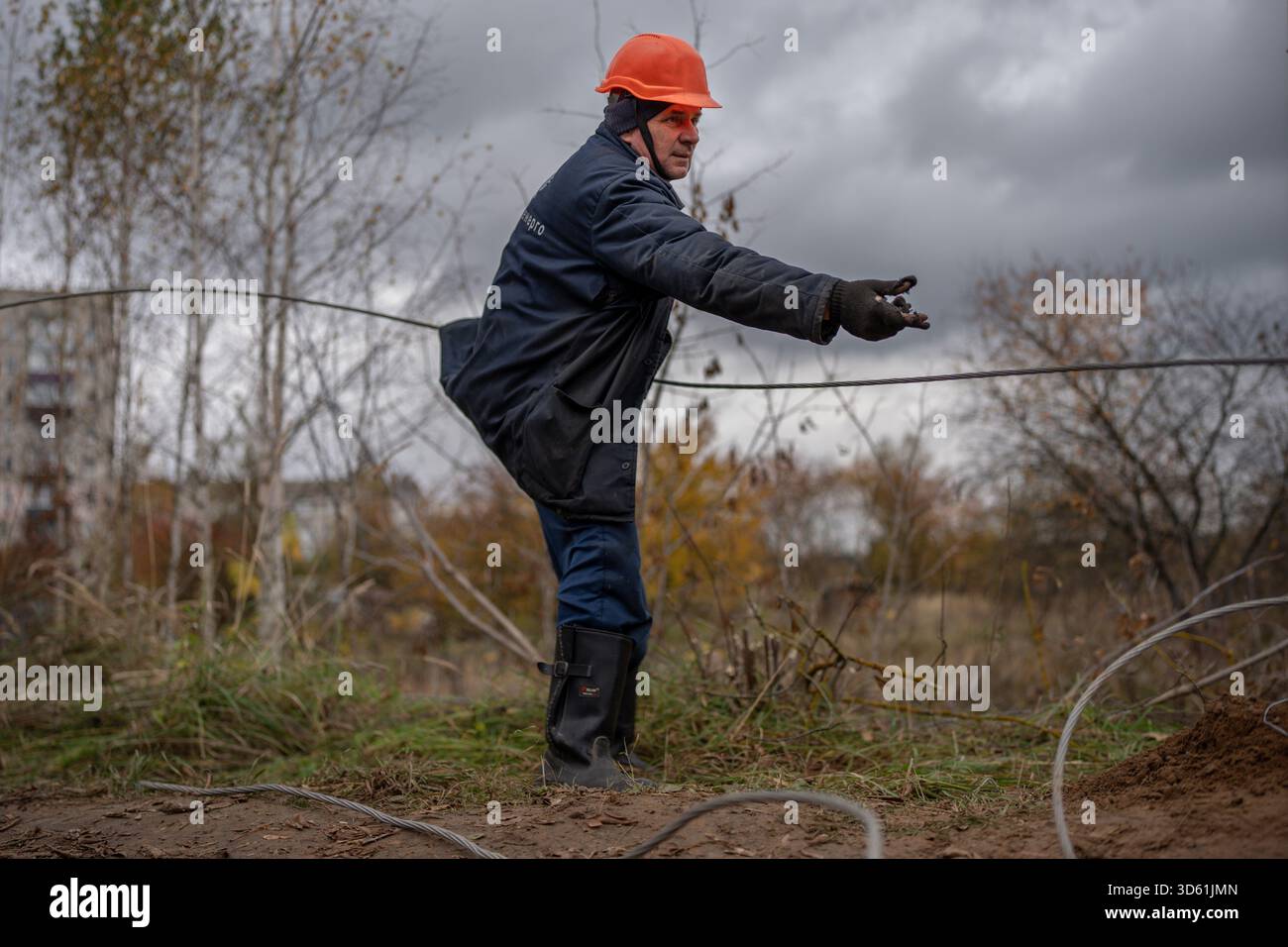 Wearing worn down gloves and uniform, a worker repairs power lines ...