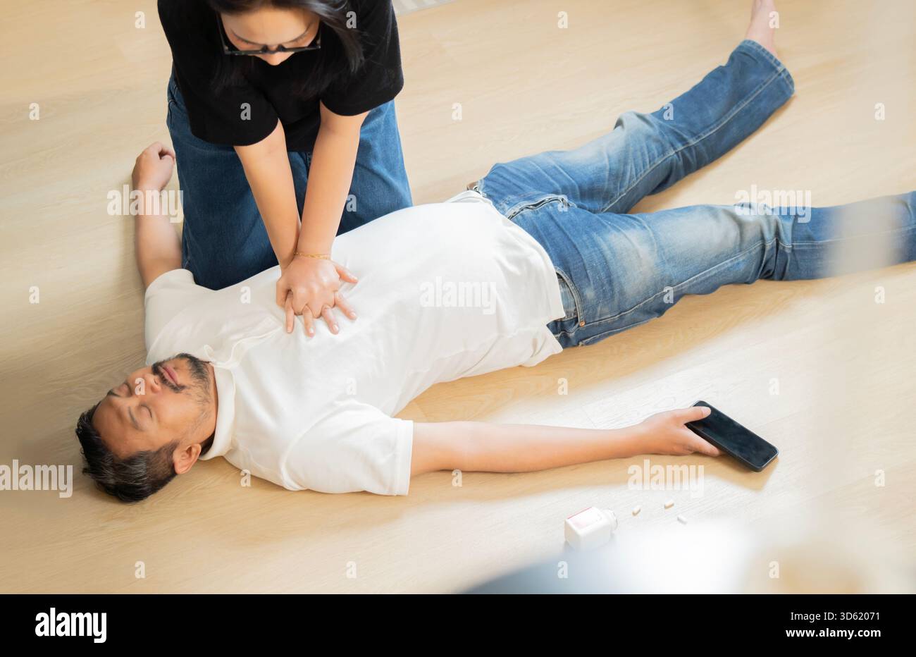 Adult Asain woman doing CPR on unconscious husband having heart attack ...