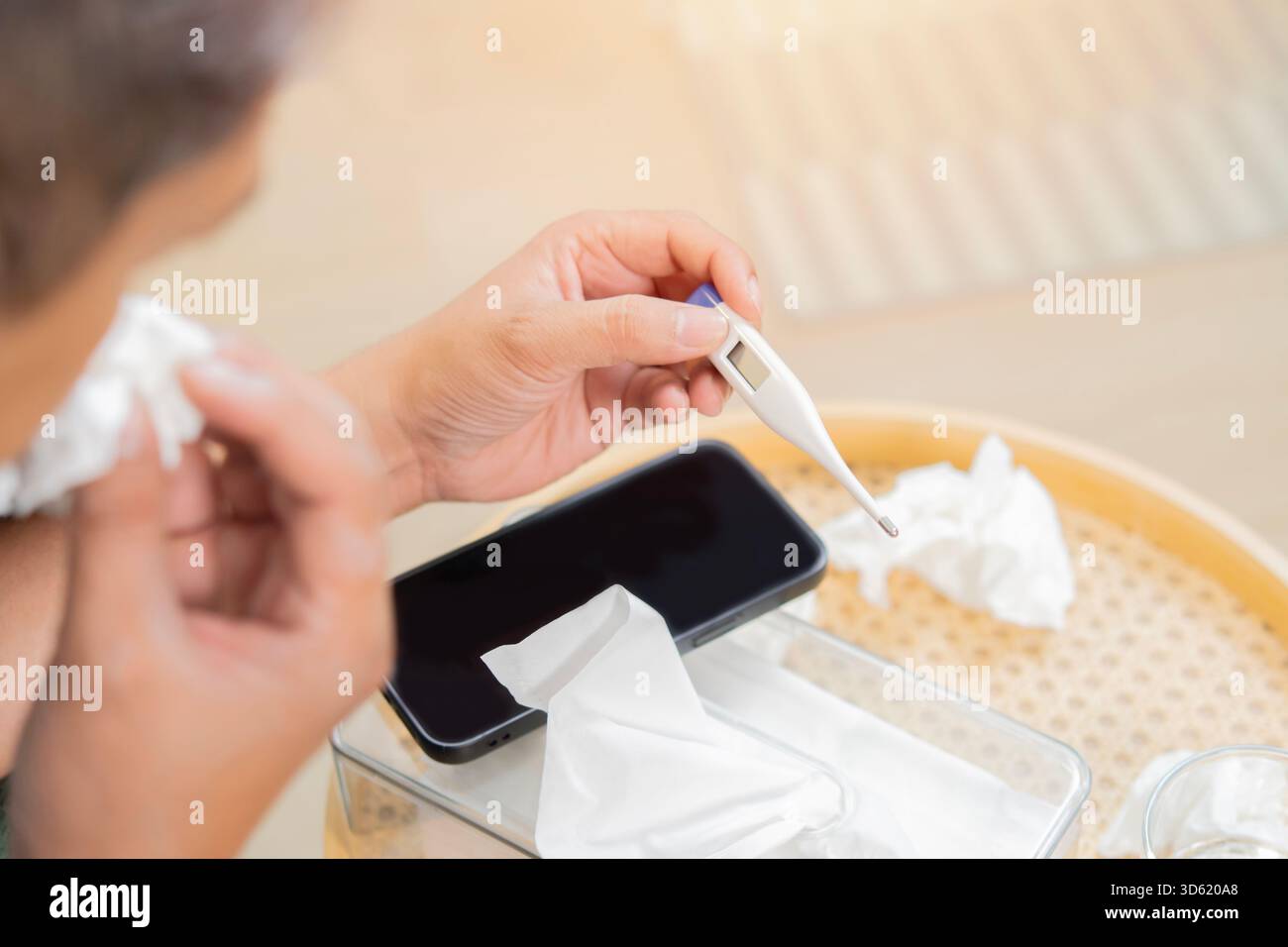 Sick mature man measuring temperature with thermometer at home. Back ...