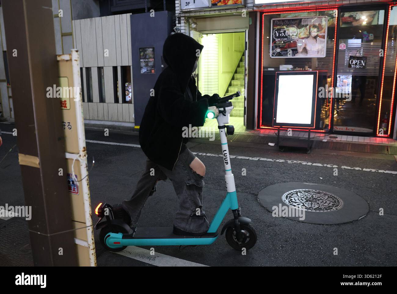 A person rides an electric kick scooter, Luup, late at night in Kabukicho, Japan's largest ...