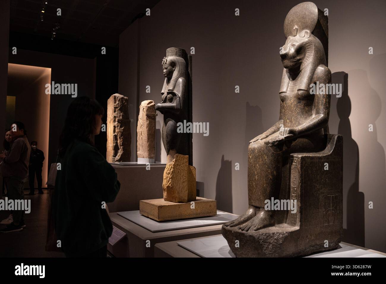 People looking at statues on display at the “Ancient Egypt Unveiled ...