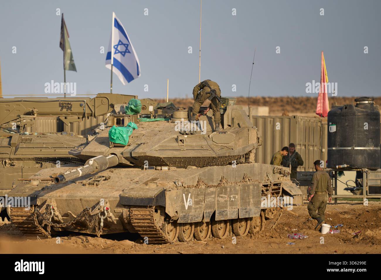 Israeli soldiers work on tanks at a staging area on the border with ...