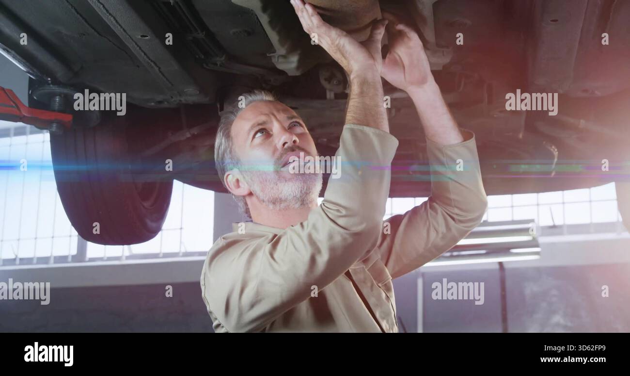 Checking mechanic in tan shirt holding exhaust beneath car on lift in ...