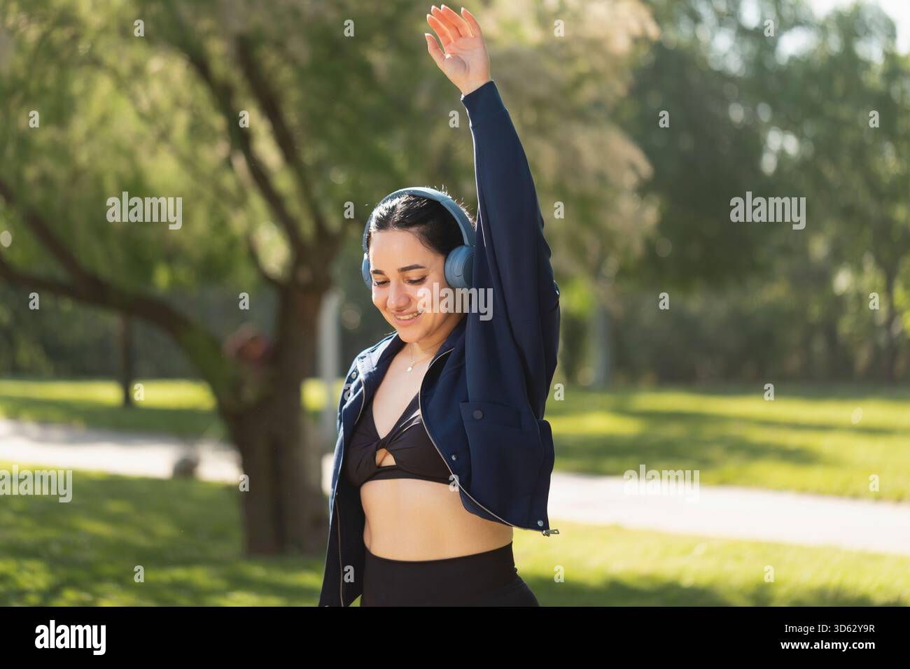 A woman performs exercise and shoulder and arm stretches in the park in the morning Stock Photo ...