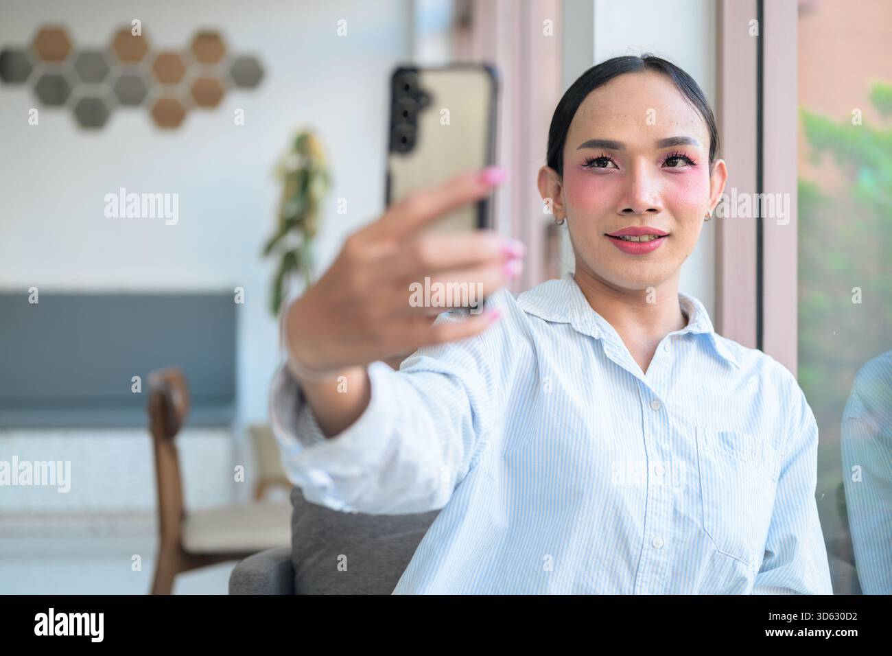 Portrait of a young Thai transgender individual with makeup and long ...