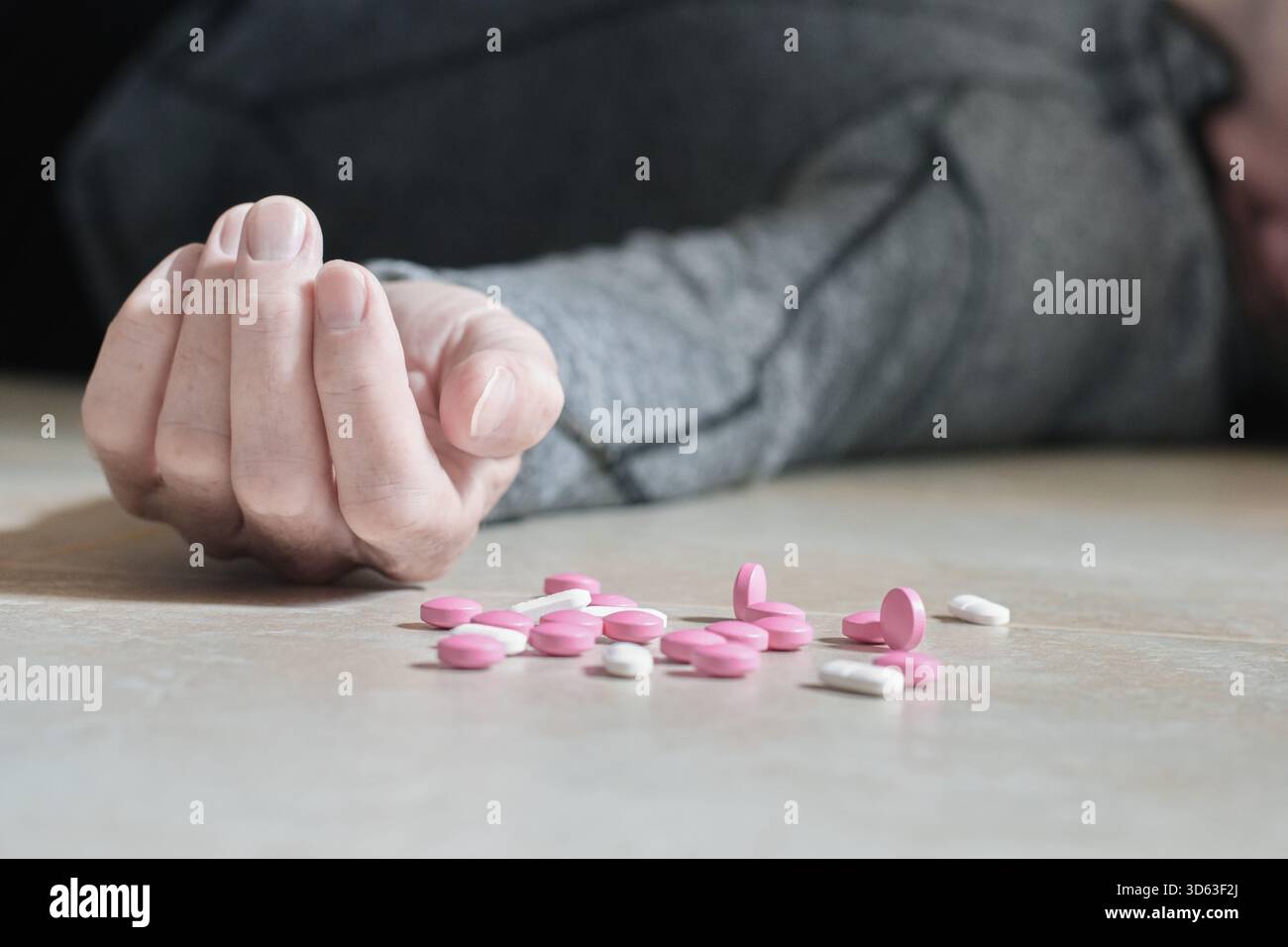 Man lying on the floor surrounded with pills, suicide, addiction ...