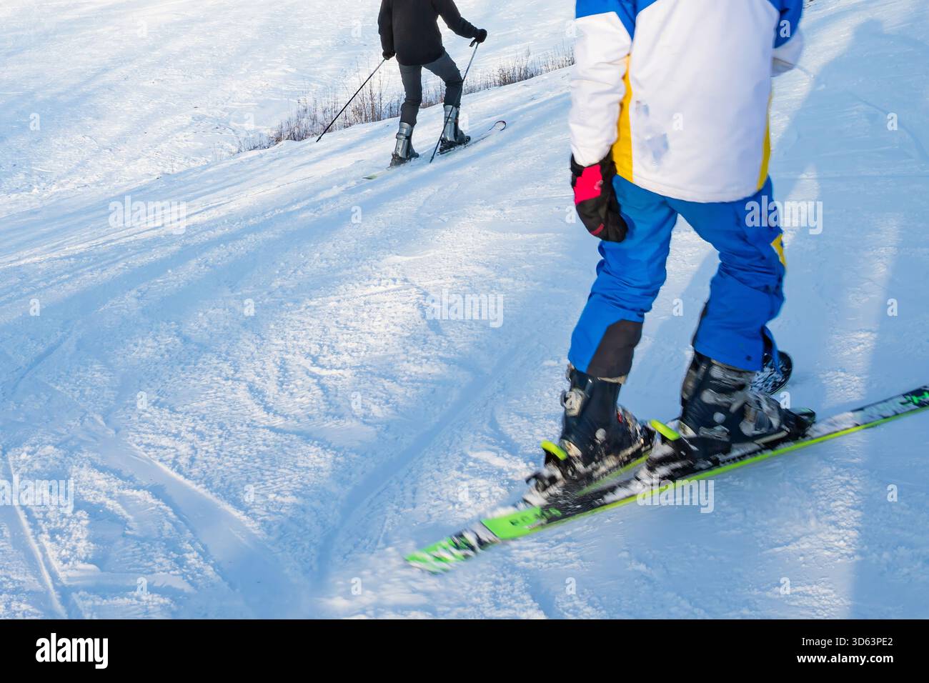 Skiers on snowy winter slope with scattered snow formations during cold ...