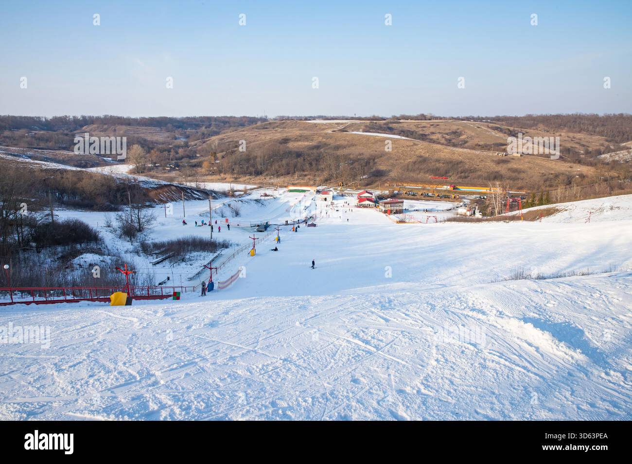 Skiers on snowy winter slope with scattered snow formations during cold ...