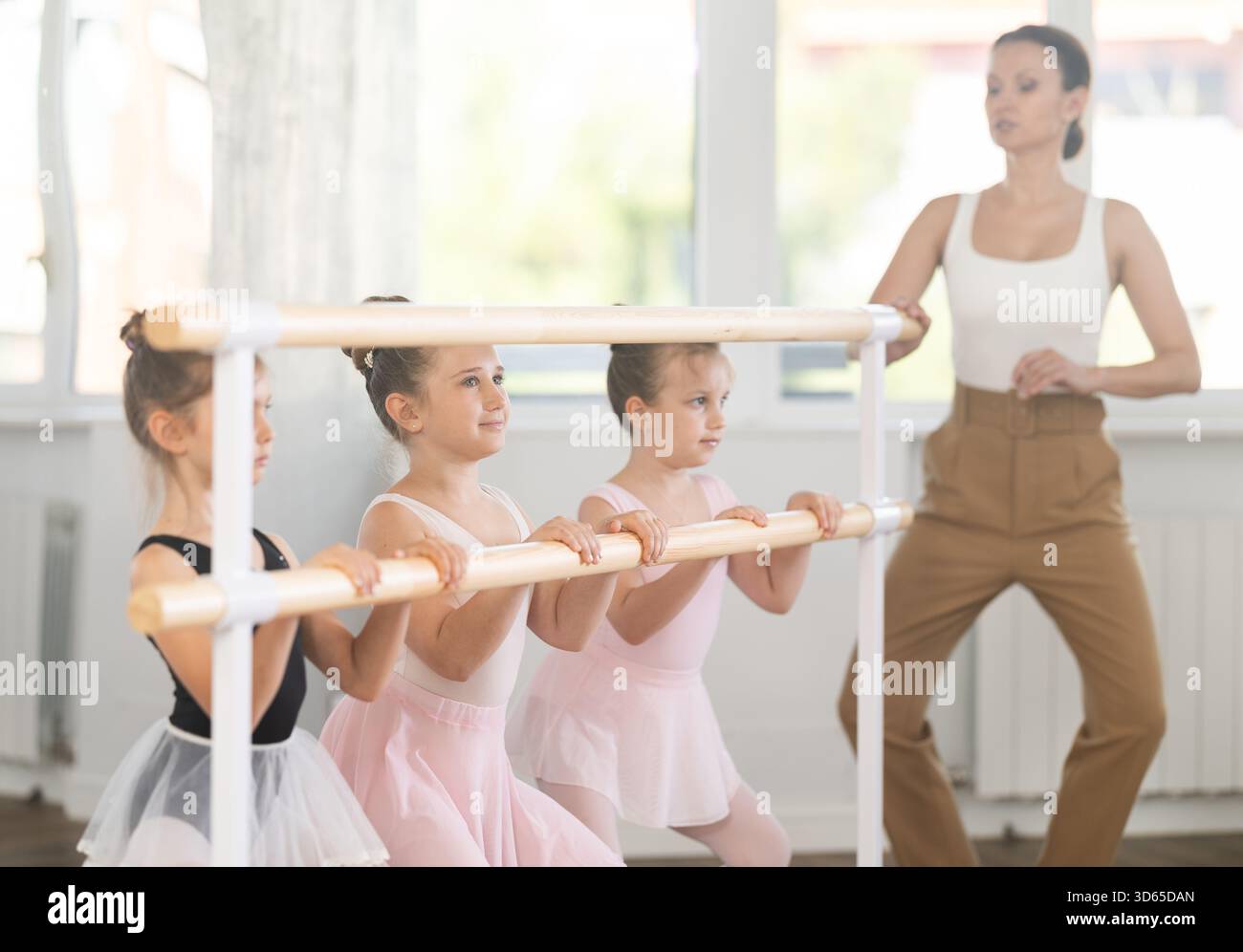 Teacher conducts class with children girls in ballet studio, observes ...