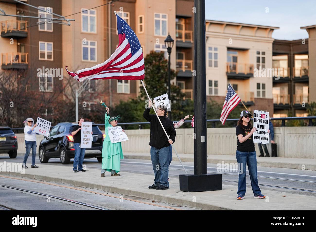 Protesters hold signs and flags amidst the arrival of federal law ...