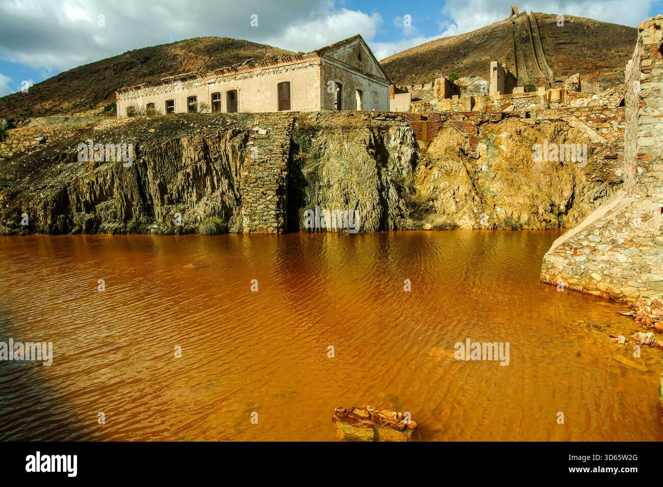 Vivid reddish-brown lagoon sits below the remains of a copper smelting ...