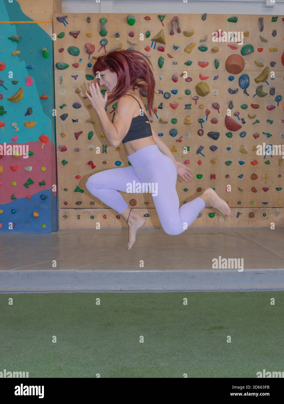 Woman jumping powerfully on a climbing wall preparing to climb Stock ...